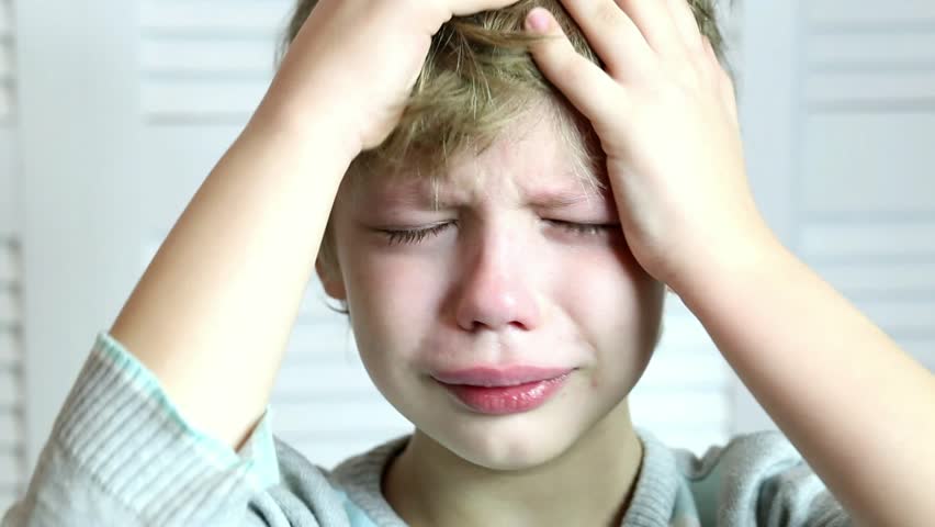 portrait of 8 years old boy crying and looking at camerae. family ...
